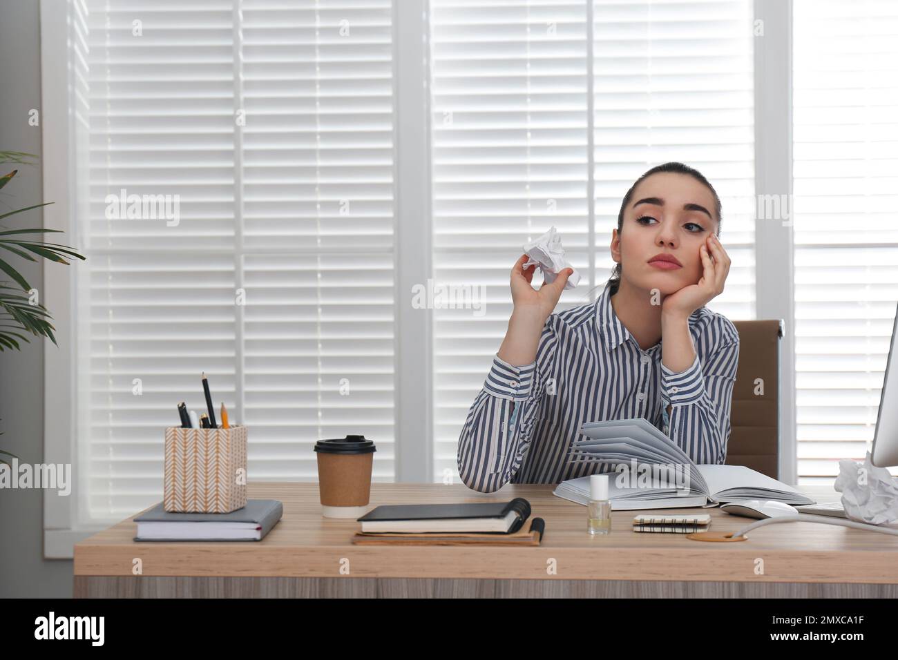 Lazy employee playing with crumpled paper at table in office Stock ...