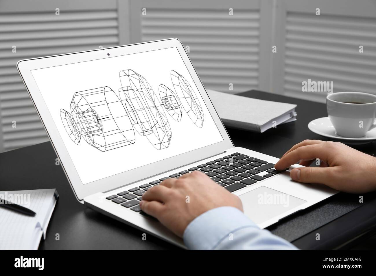 Male engineer working with 3d model of modern equipment on laptop ...