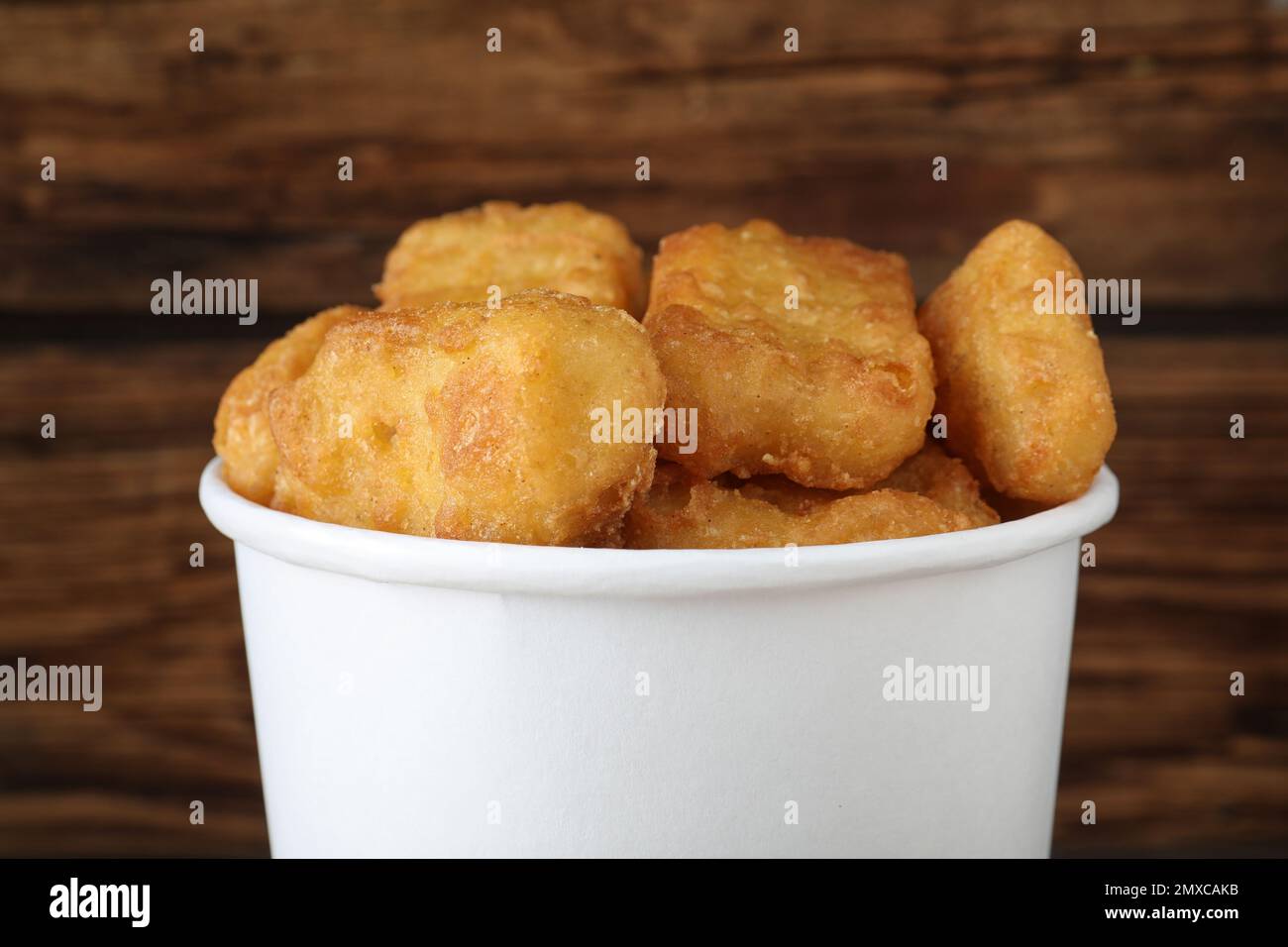 Bucket with tasty chicken nuggets on wooden background, closeup Stock ...