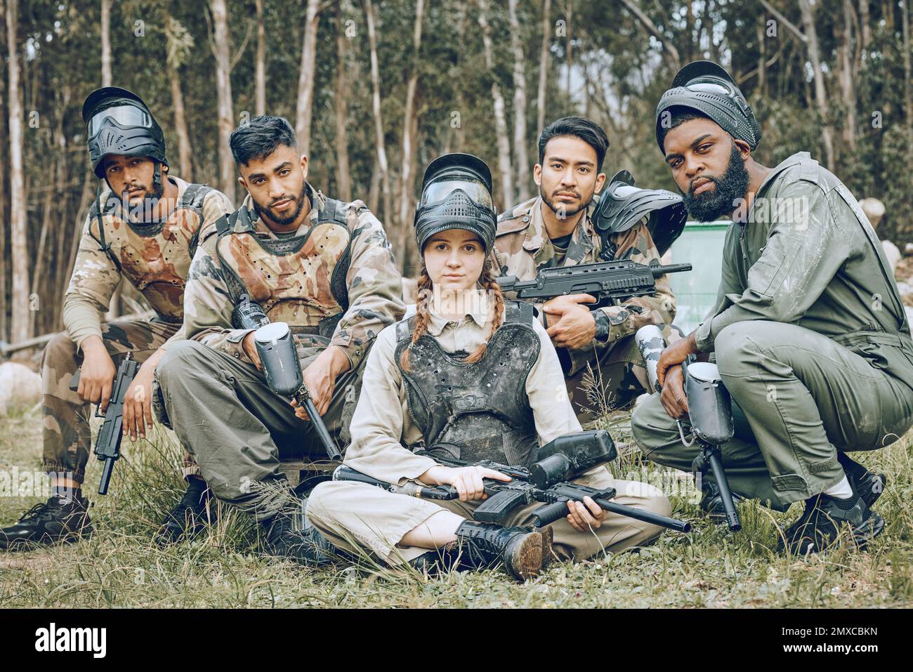Paintball, portrait or team in a shooting game playing or training on a ...