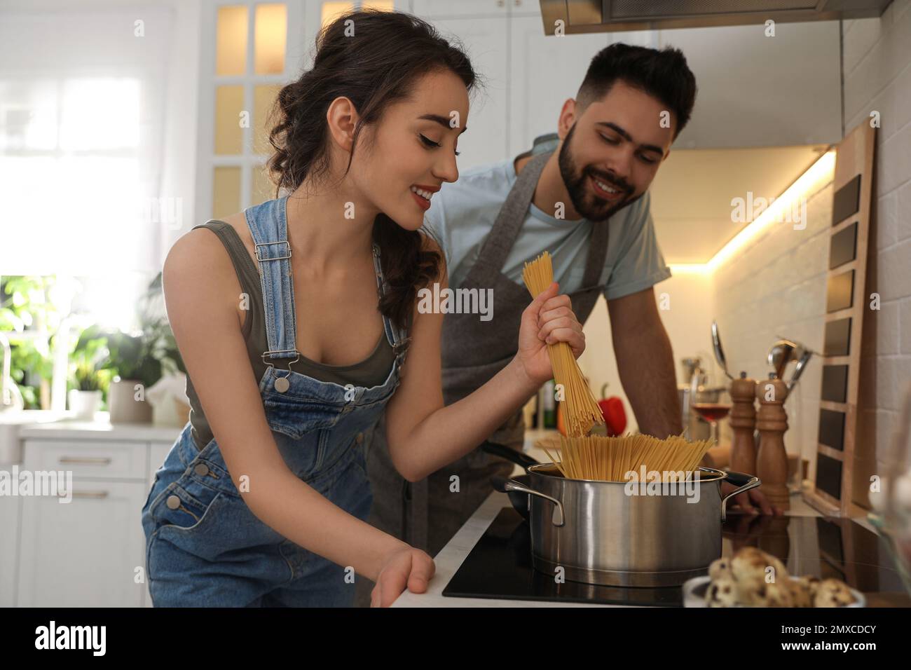 Lovely young couple cooking pasta together in kitchen Stock Photo - Alamy