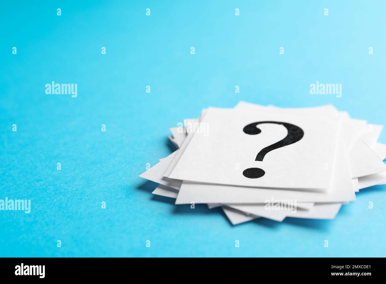 Heap of paper notes with question marks on light blue background ...