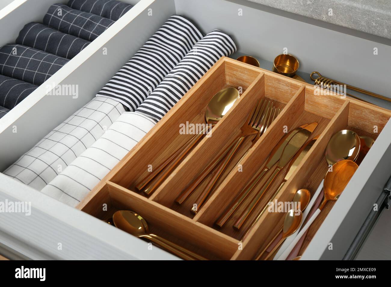 Open drawer with different utensils and folded towels. Order in kitchen ...