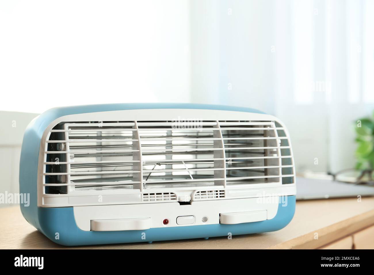 Modern air purifier on wooden table in room Stock Photo - Alamy