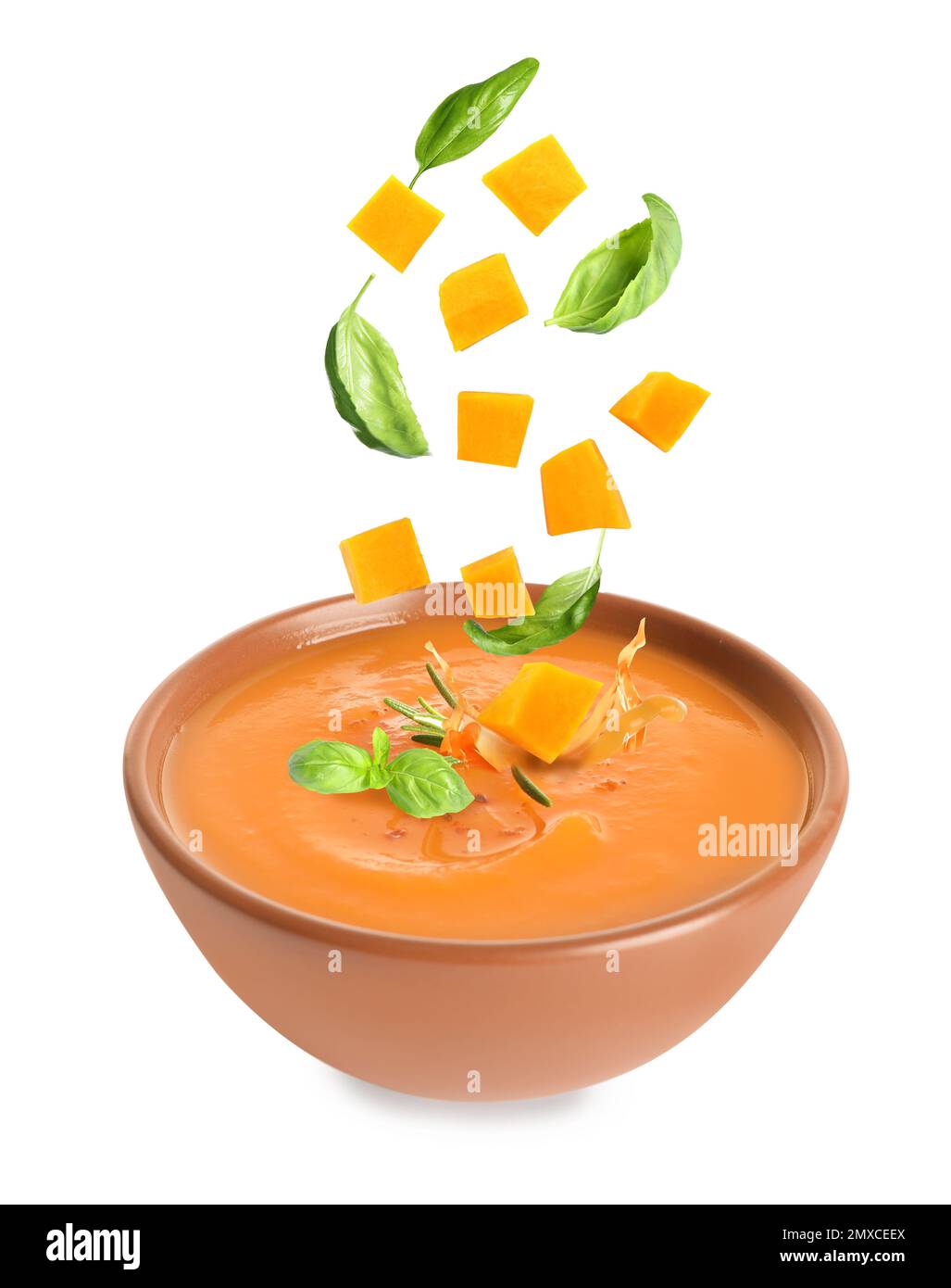 Ingredients falling into bowl of homemade pumpkin soup on white ...