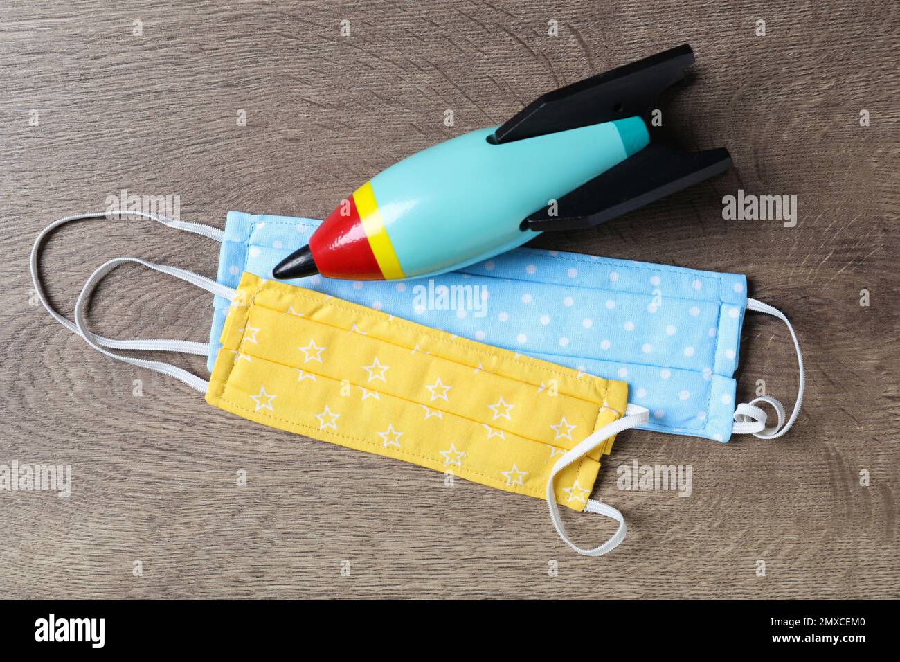 Homemade protective masks and toy rocket on wooden background, flat lay ...