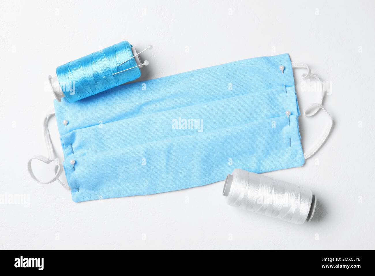 Handmade protective mask with sewing pins and threads on white ...