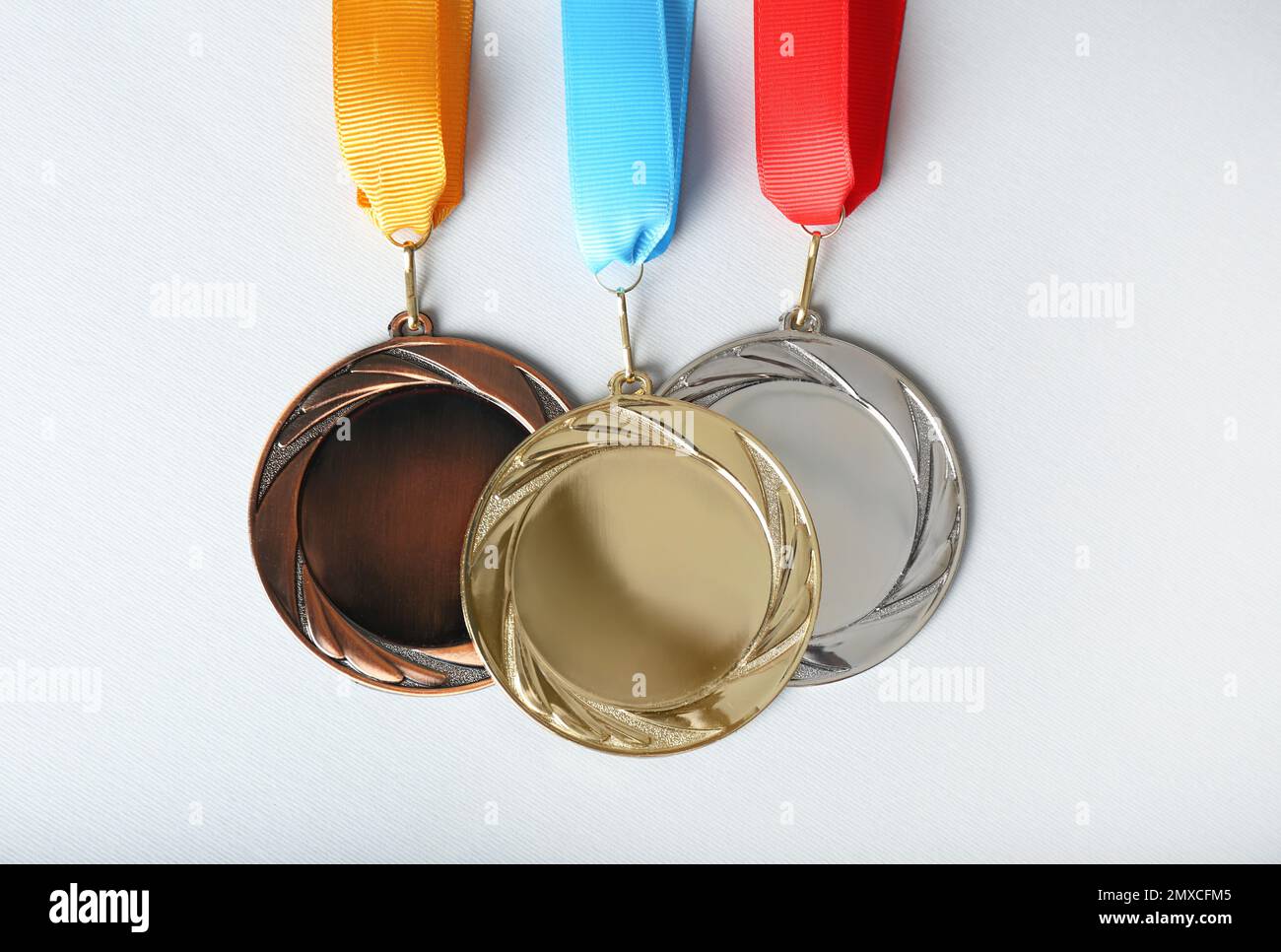 Gold, silver and bronze medals on white background, flat lay. Space for ...