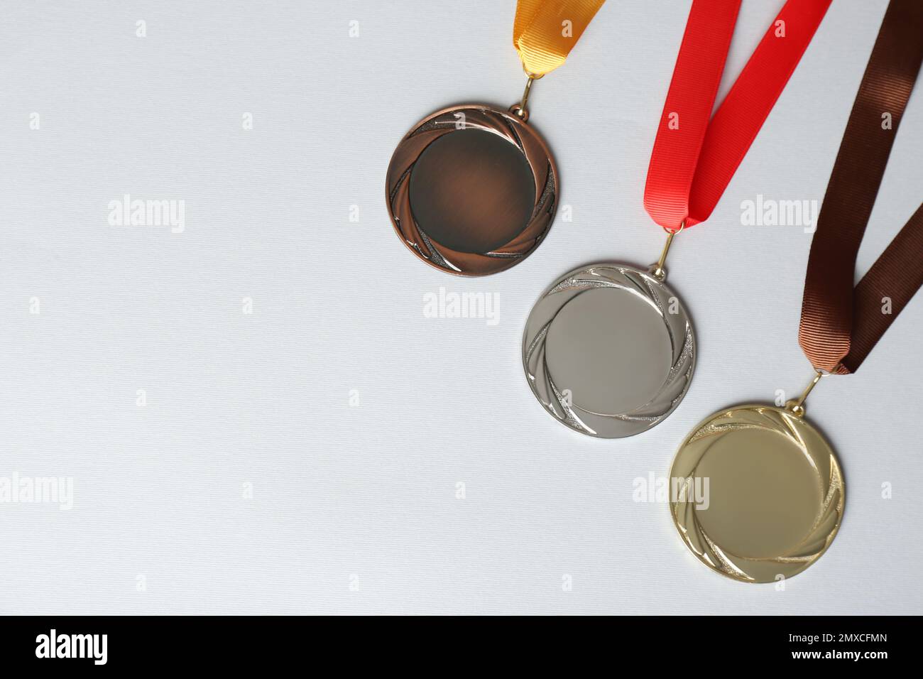 Gold, silver and bronze medals on white background, flat lay. Space for ...