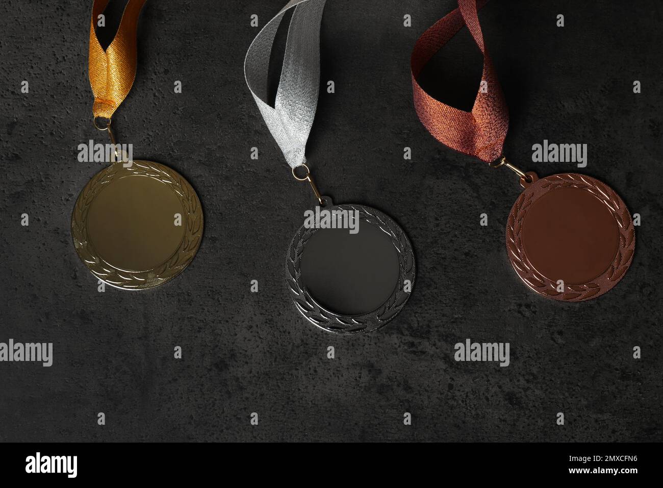 Gold, silver and bronze medals on grey stone background, flat lay ...