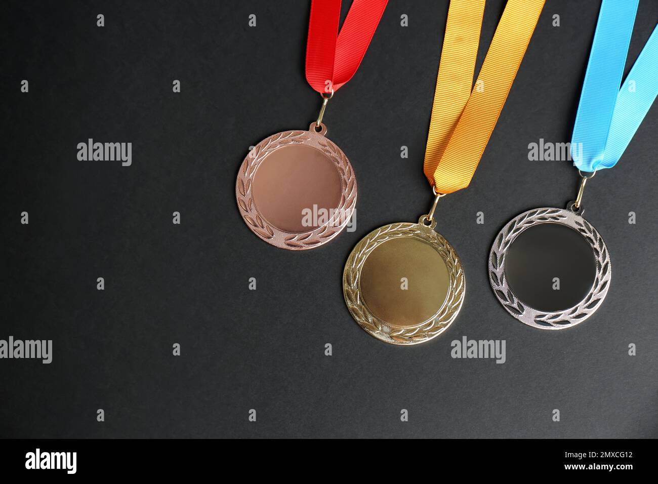 Gold, silver and bronze medals on black background, flat lay. Space for ...