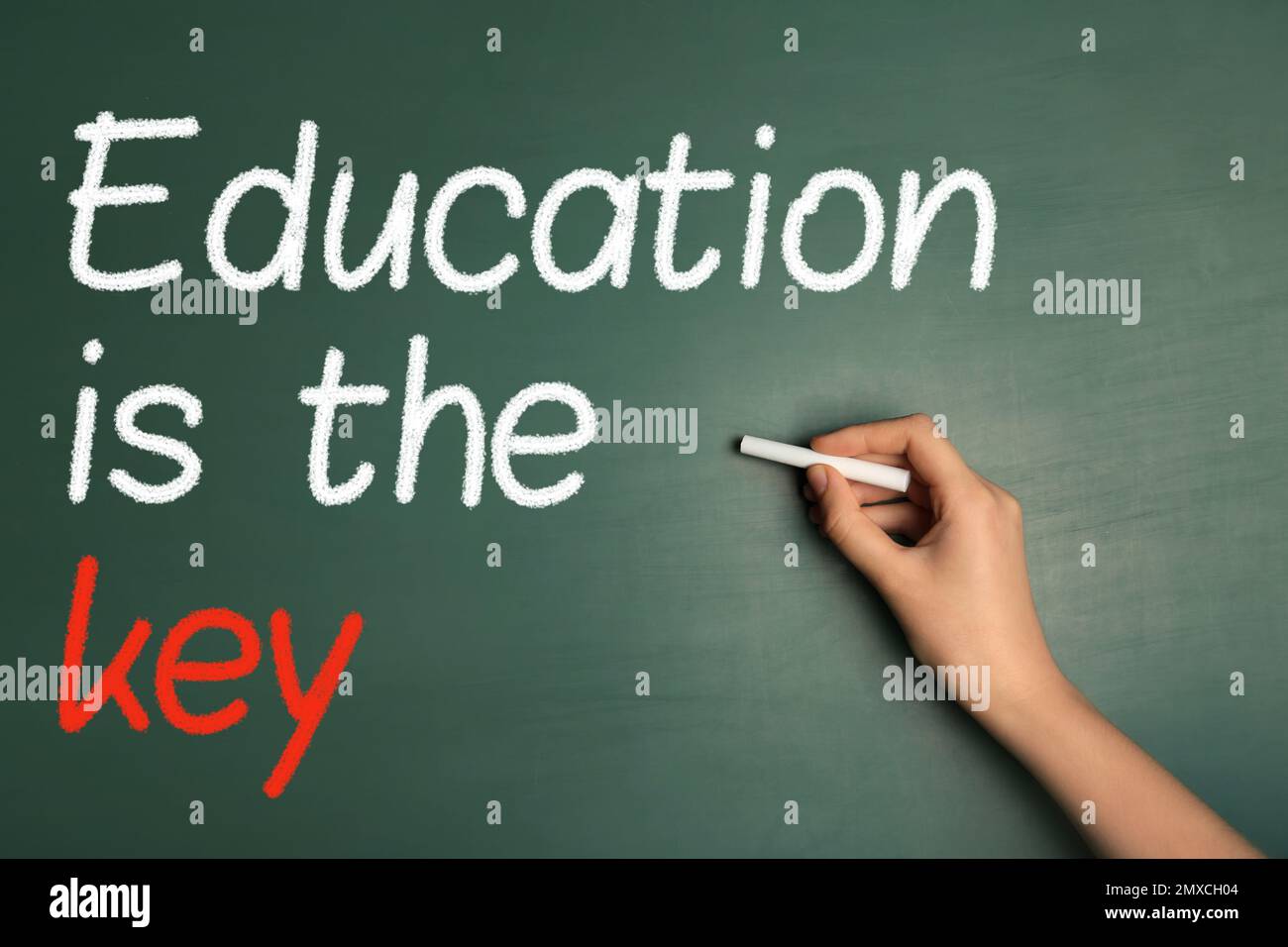 Woman writing phrase Education is the key on chalkboard, closeup. Adult ...