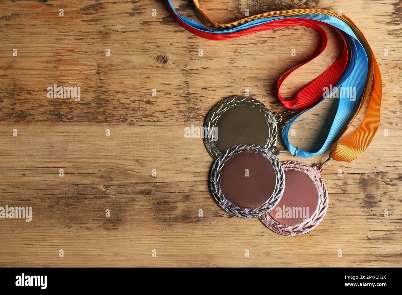 Gold, silver and bronze medals on wooden background, flat lay. Space ...