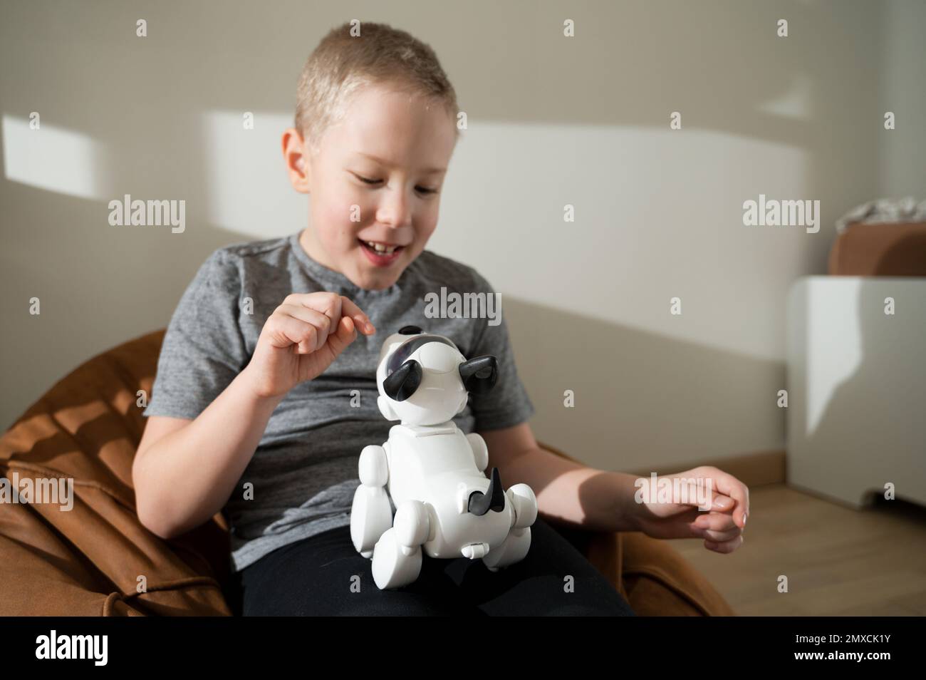 Boy playing with robotic dog, giving command to dog Stock Photo - Alamy