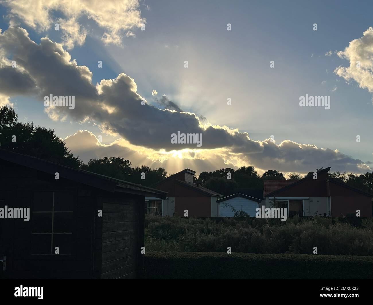 A bright sunrise in the clouds over the houses Stock Photo - Alamy
