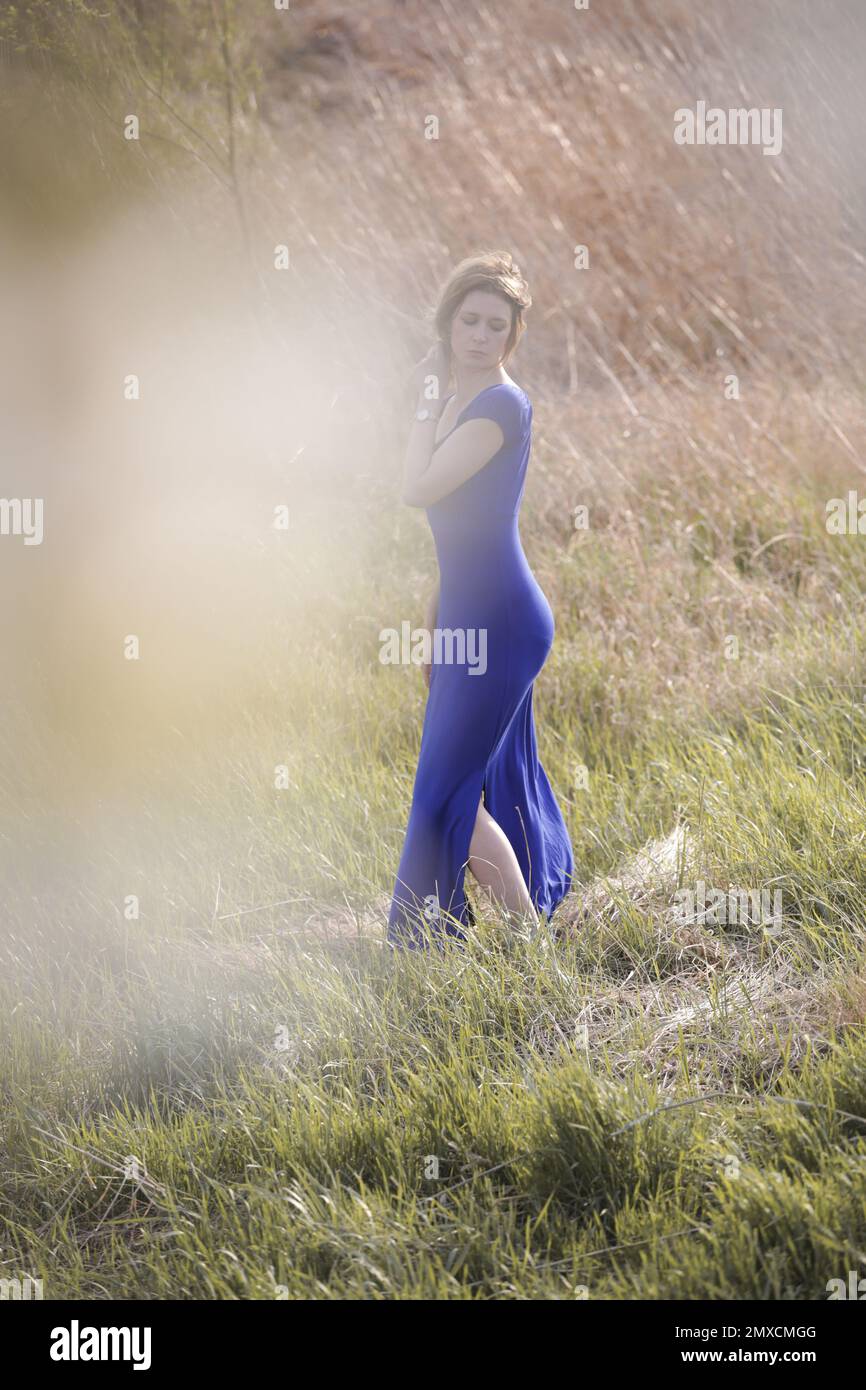 Outdoor portrait of female model in blue maxi dress enjoying in nature ...
