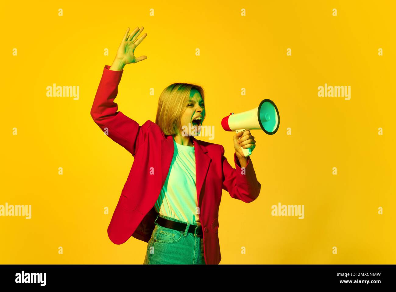 Excited young girl shouting in megaphone isolated over bright yellow ...