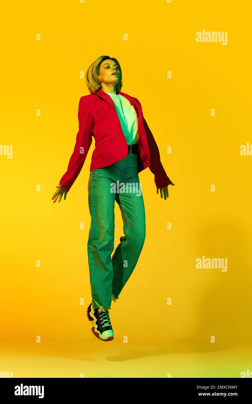 Young girl moves above ground, levitating over yellow background ...