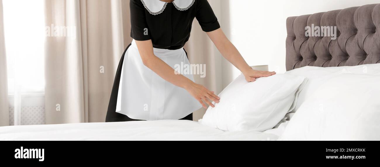 Young maid making bed in hotel room, closeup. Banner design Stock Photo ...