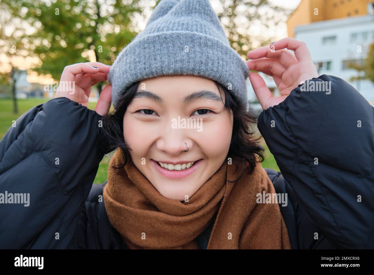 Portrait of cute asian girl in hat and scarf, walks around town in ...