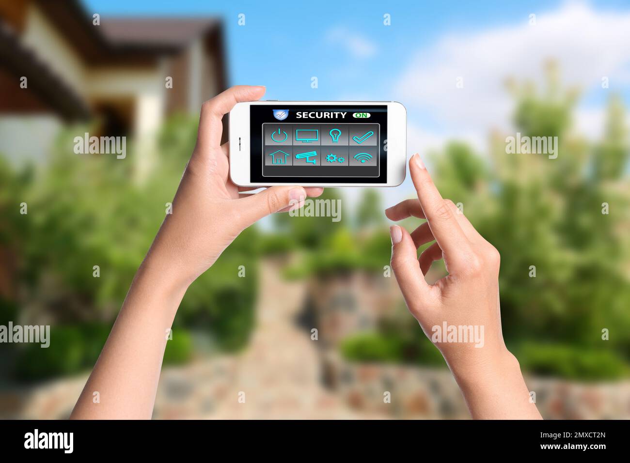 Woman monitoring modern CCTV cameras on smartphone near her house ...