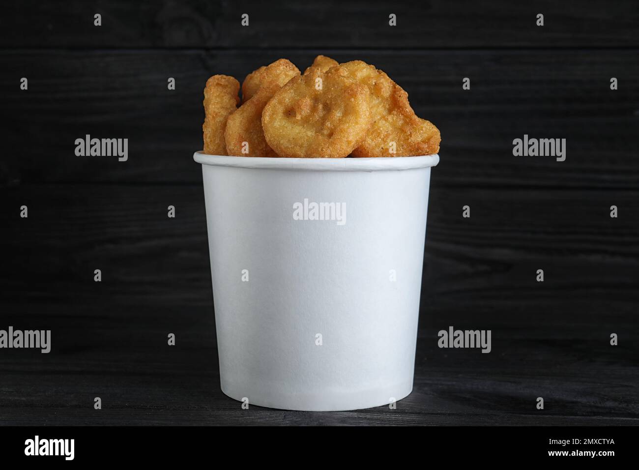 Bucket with tasty chicken nuggets on black table Stock Photo - Alamy