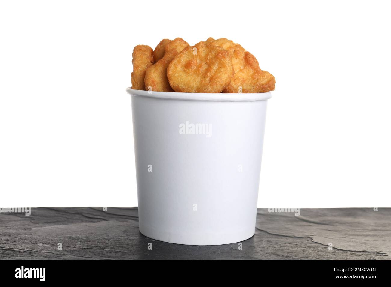 Bucket with tasty chicken nuggets on black table against white ...