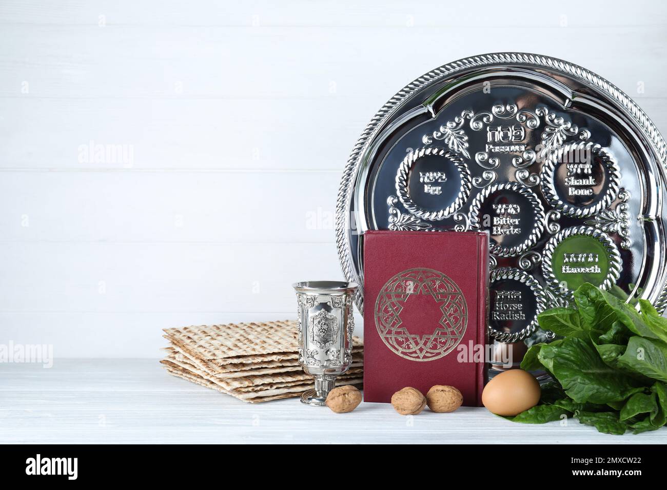 Symbolic Pesach (Passover Seder) items on white wooden table. Space for ...
