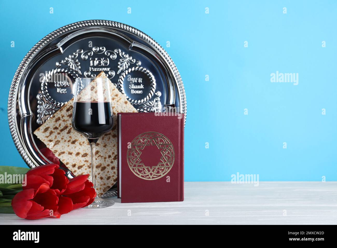 Symbolic Pesach (Passover Seder) items on white wooden table. Space for ...