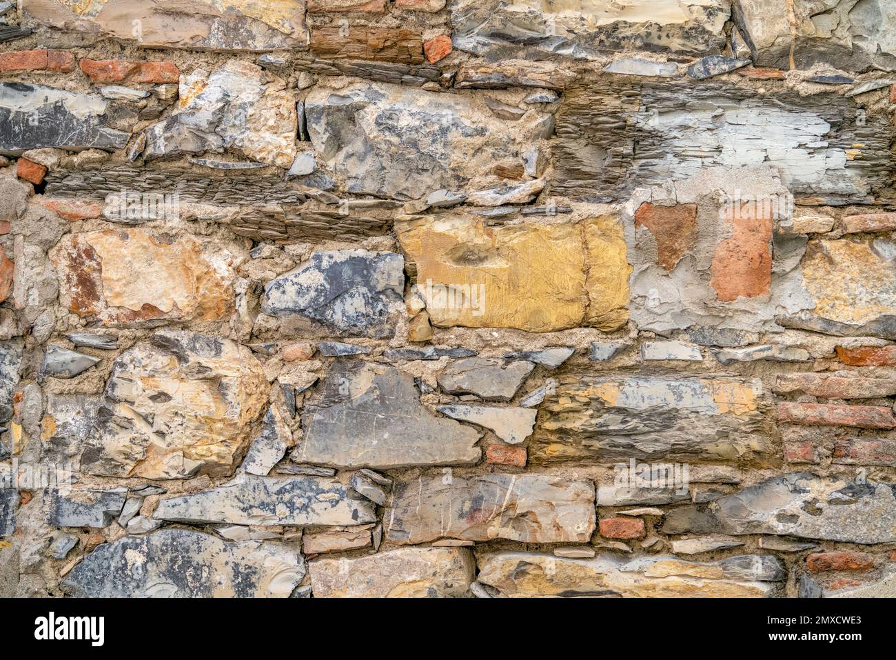 Full frame frontal detail of a vivid stone wall made of various stone ...