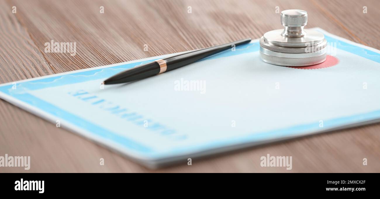 Certificate form, notary stamp and pen on wooden table, closeup. Banner ...