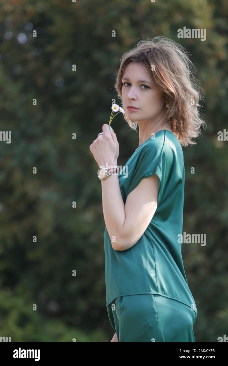 Outdoor portrait of female model in silk green outfit enjoying a ...