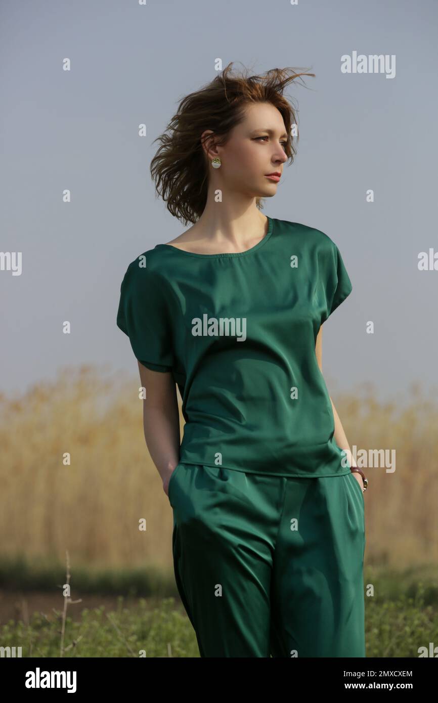 Outdoor portrait of female model in silk green outfit enjoying a ...