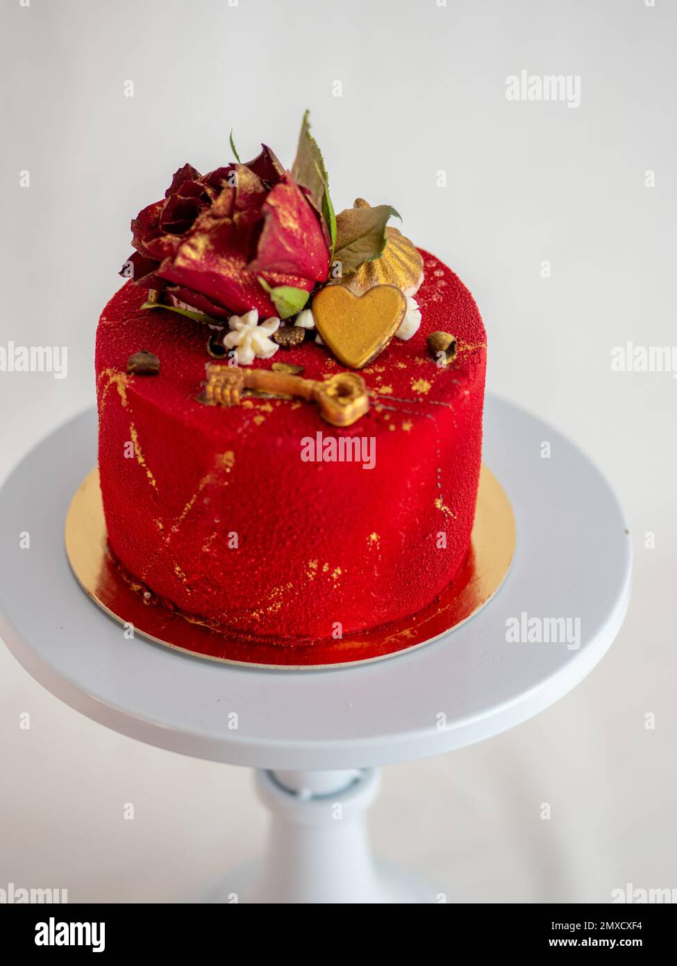 frosted red velvet cake with flower and heart toppers and golden paint ...