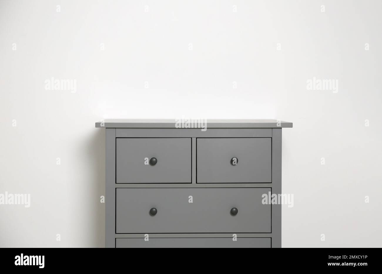 Grey chest of drawers on light background Stock Photo - Alamy