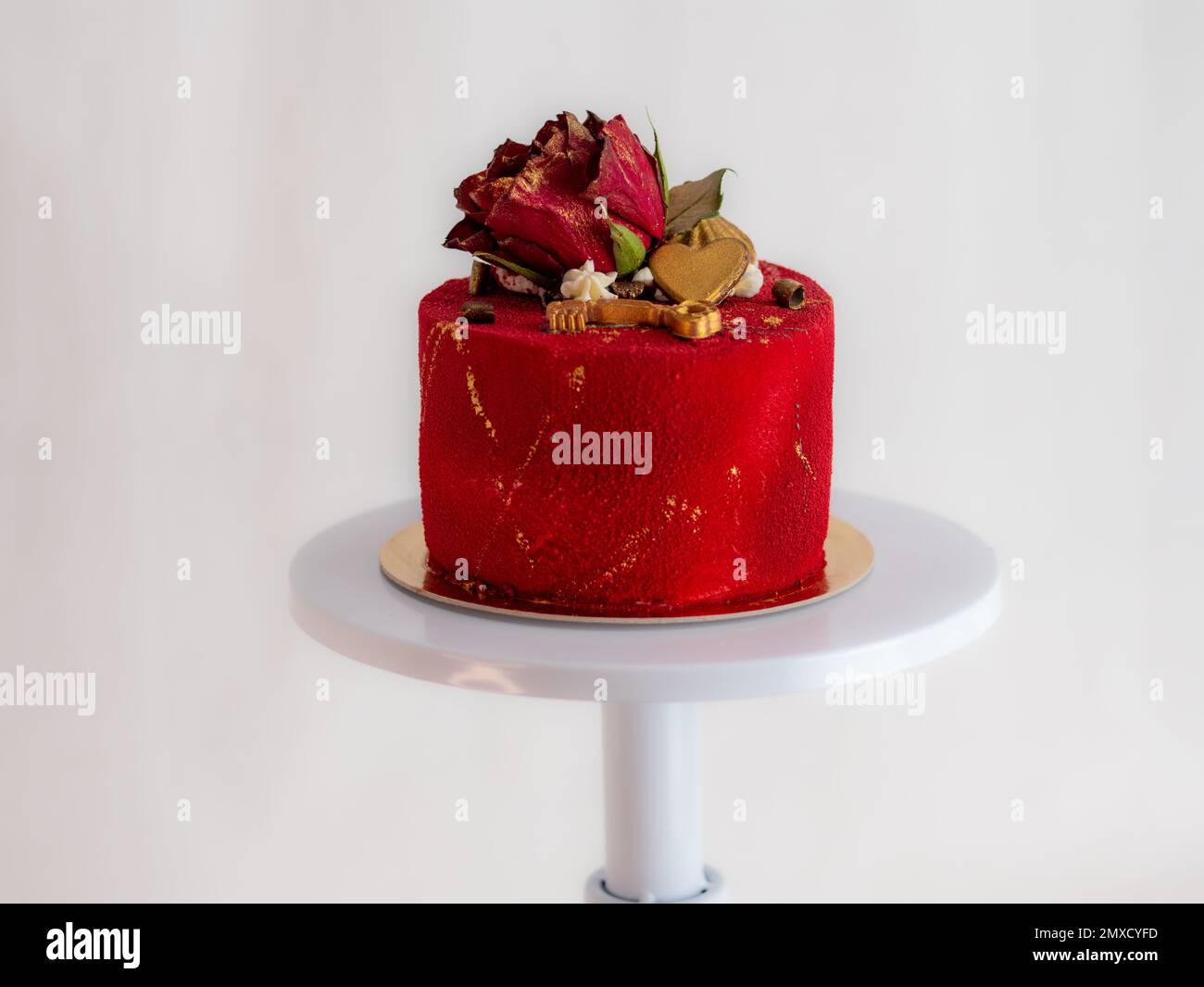 frosted red velvet cake with flower and heart toppers and golden paint ...