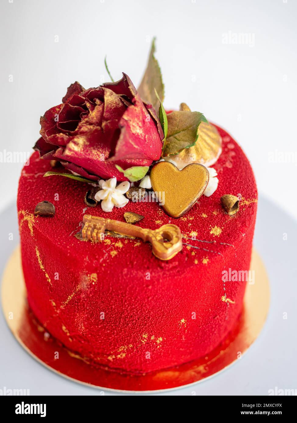 frosted red velvet cake with flower and heart toppers and golden paint ...