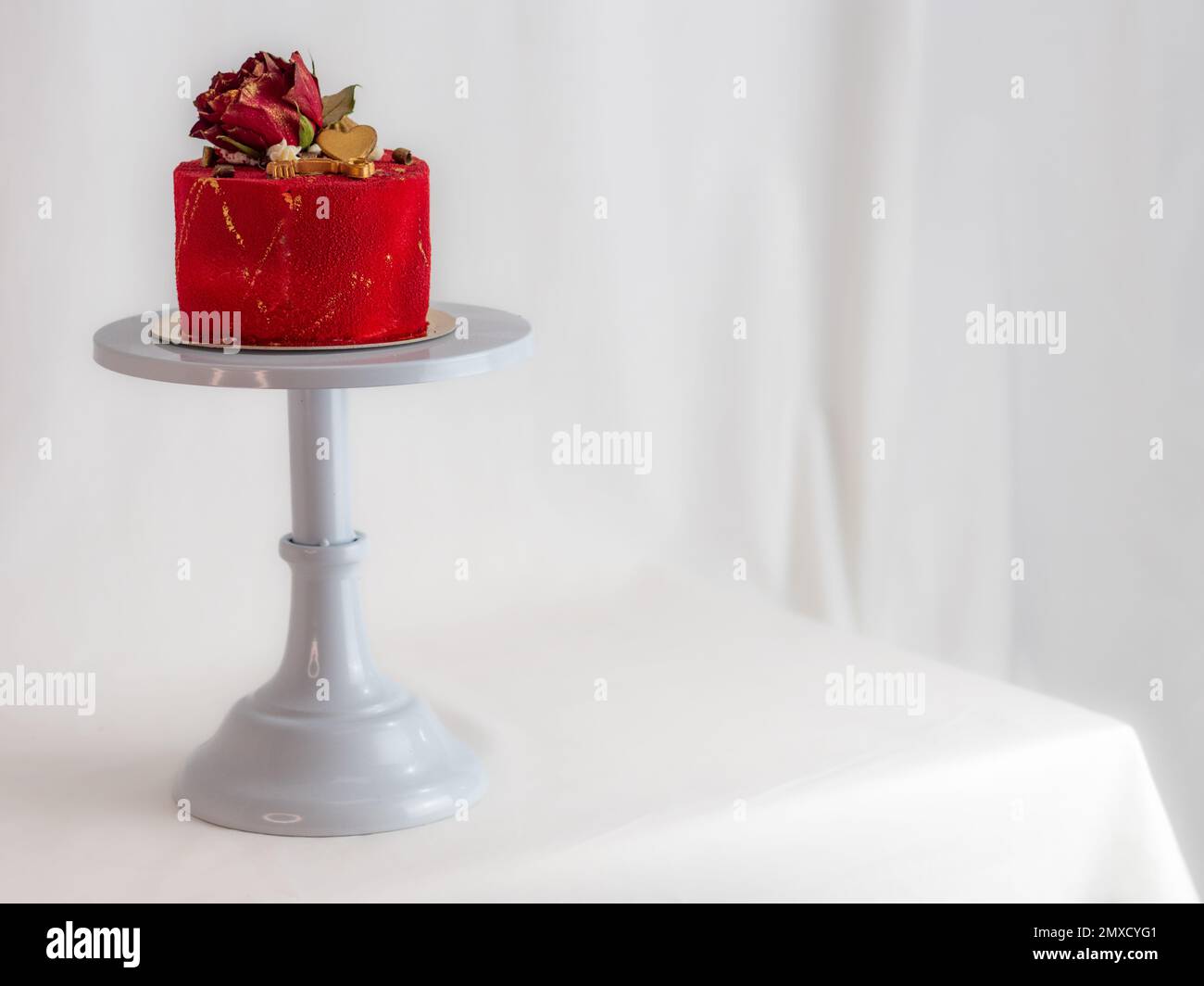 frosted red velvet cake with flower and heart toppers and golden paint ...