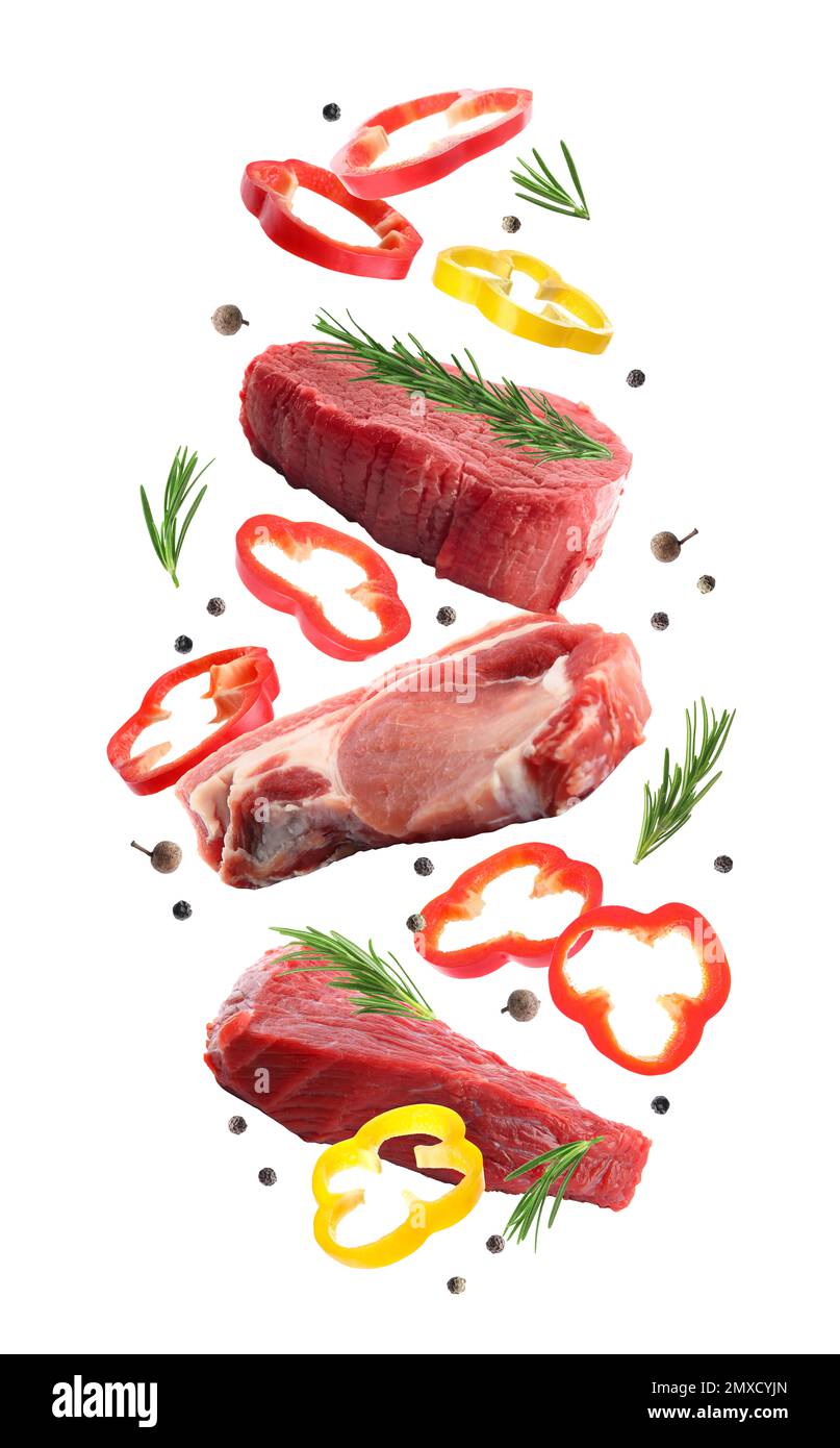 Raw beef meat and other ingredients falling on white background Stock ...