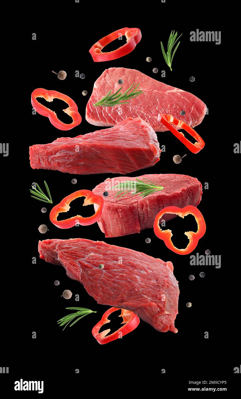 Raw beef meat and other ingredients falling on black background Stock ...