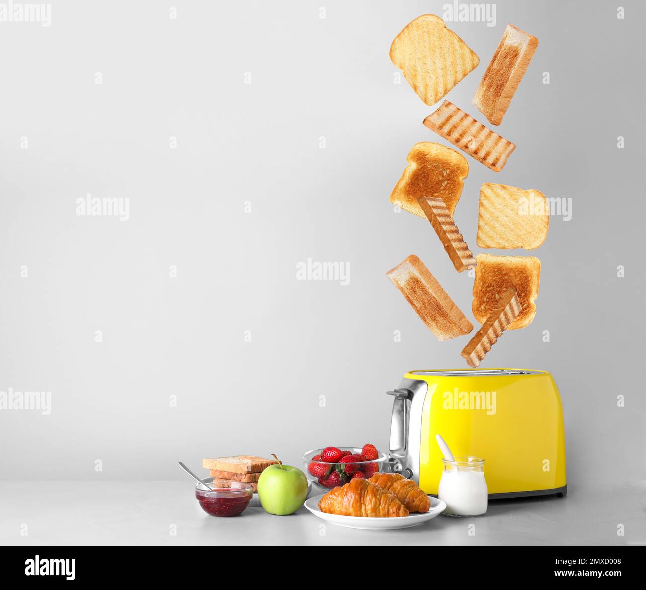 Slices of grilled wheat bread flying out of toaster on light grey table ...