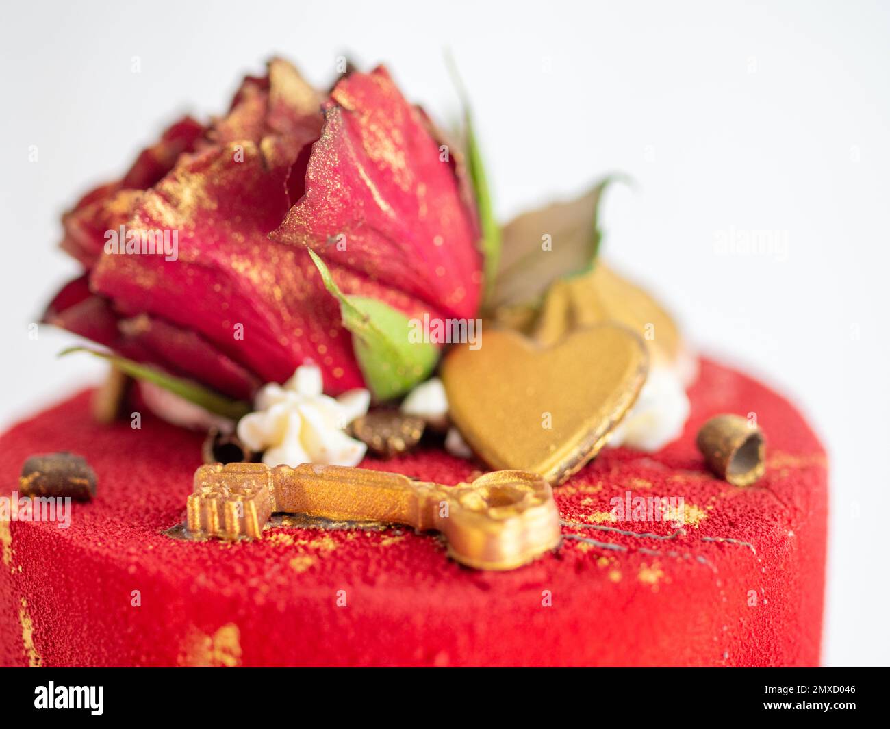 frosted red velvet cake with flower and heart toppers and golden paint ...