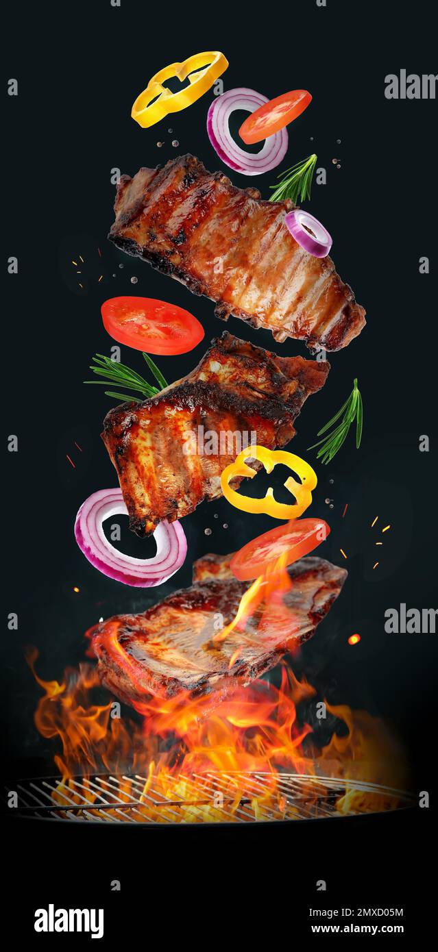 Tasty roasted meat and vegetables falling on barbecue grill with ...