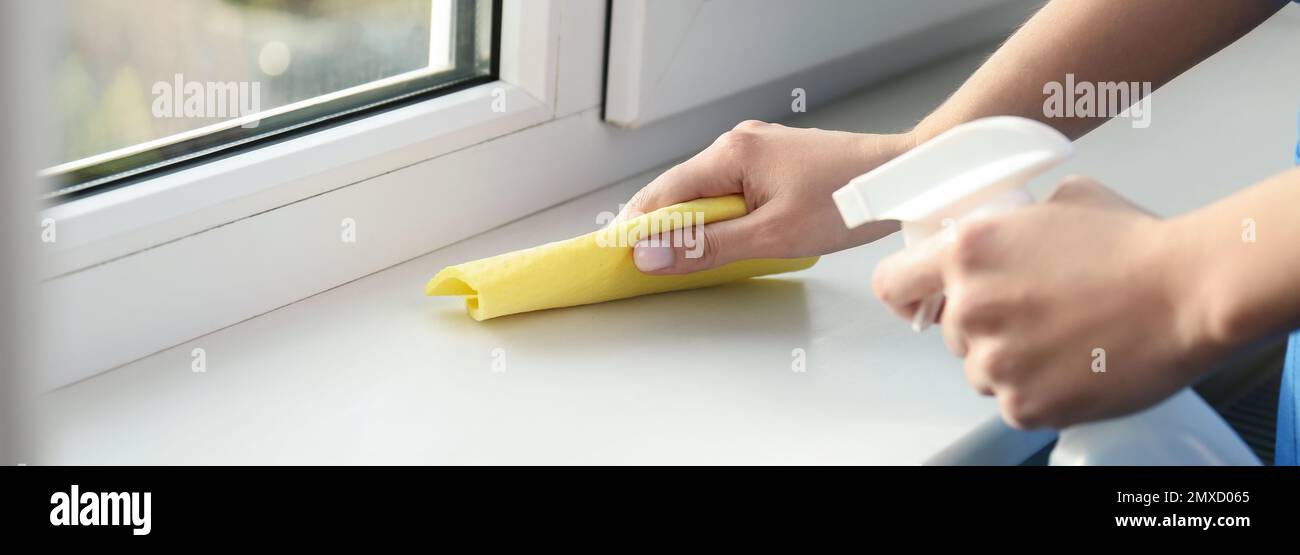 Woman cleaning window sill with rag and detergent indoors, closeup ...