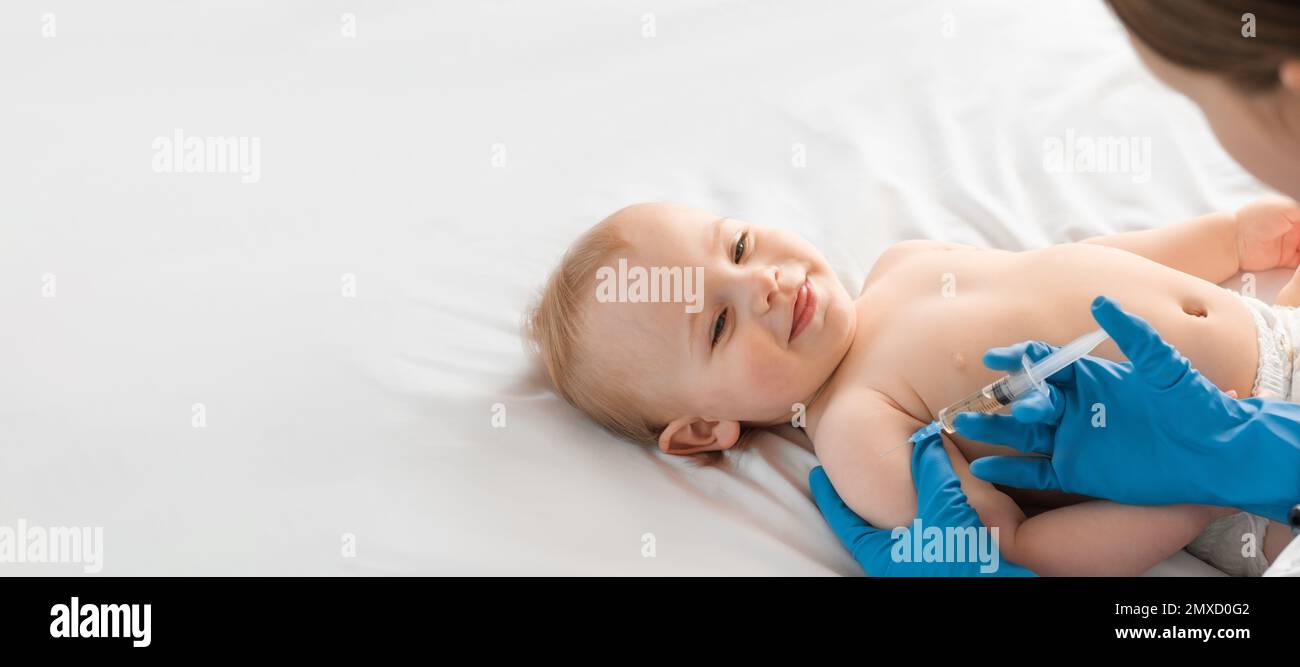 Doctor vaccinating smiling baby in clinic. One Year Little baby get an ...