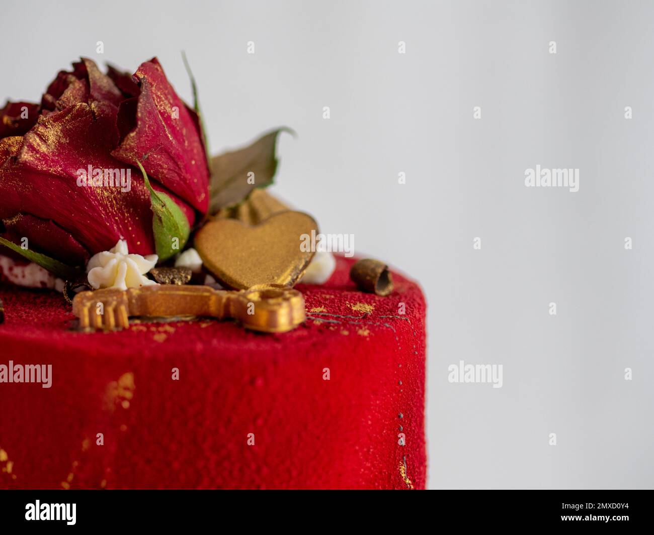 frosted red velvet cake with flower and heart toppers and golden paint ...