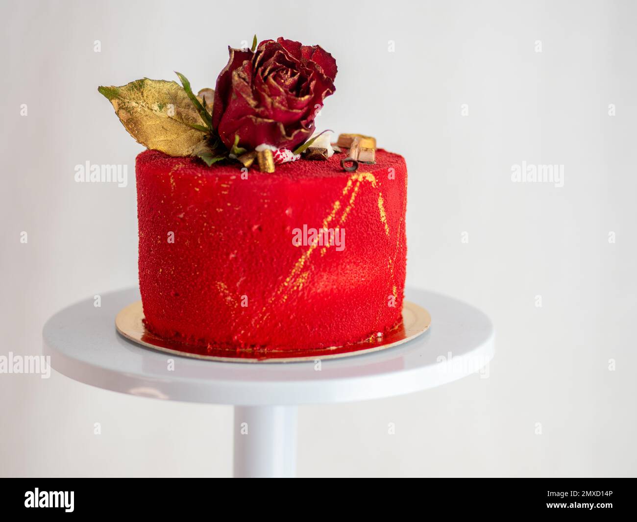 frosted red velvet cake with flower and heart toppers and golden paint ...