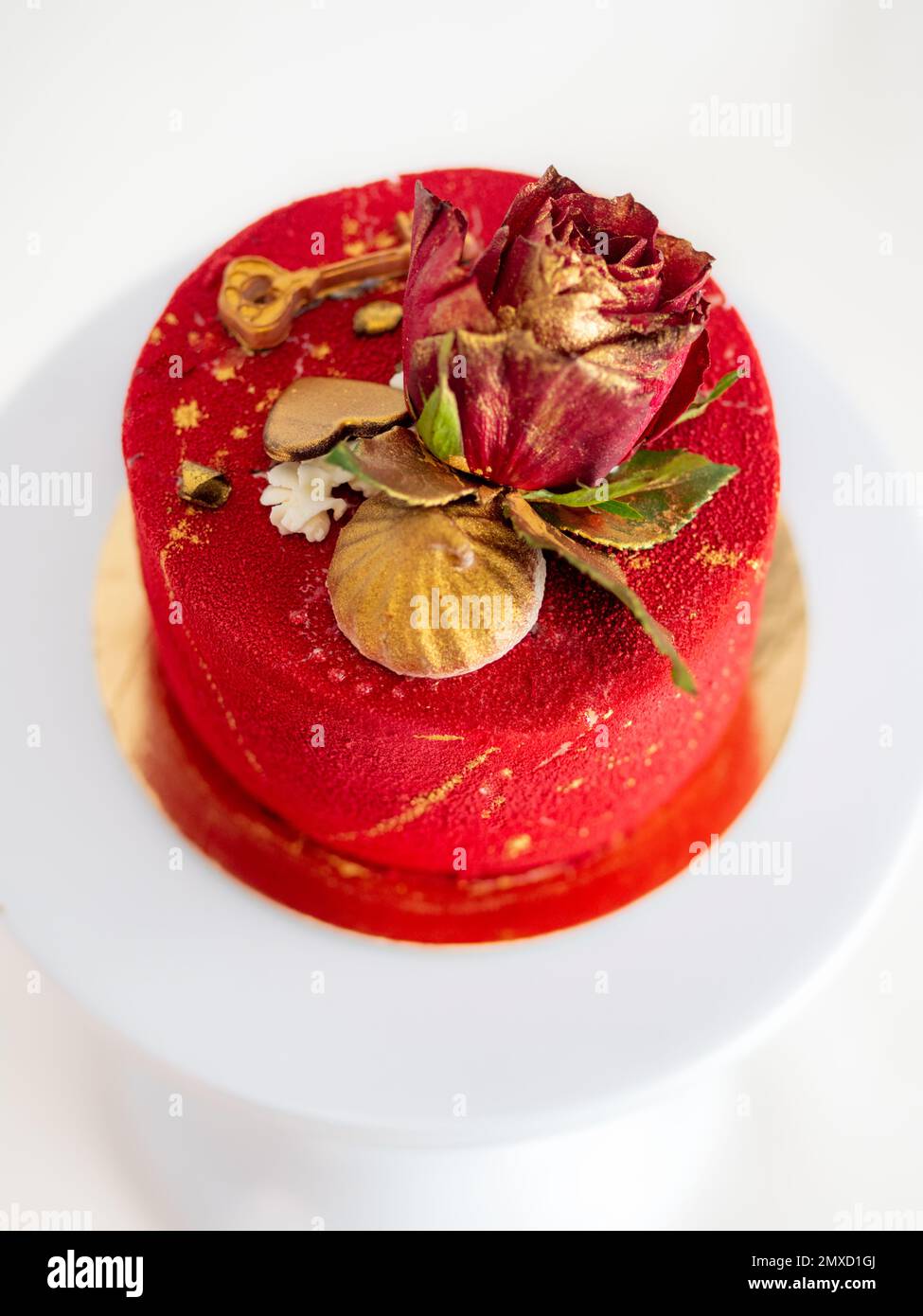 frosted red velvet cake with flower and heart toppers and golden paint ...