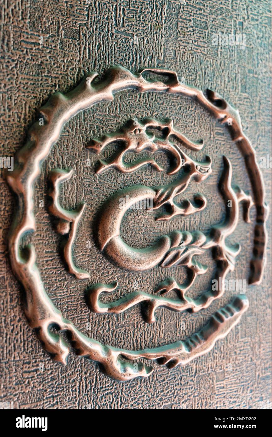 A golden statue of a traditional Chinese dragon on a rough stone wall ...