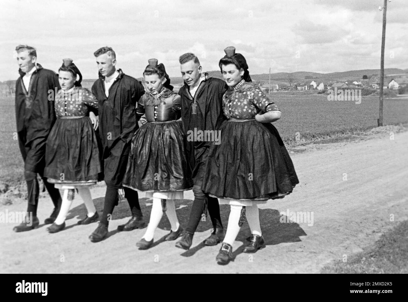 Junge Leute in Tracht laufen eine Landstraße im Schwalm-Eder-Kreis in ...